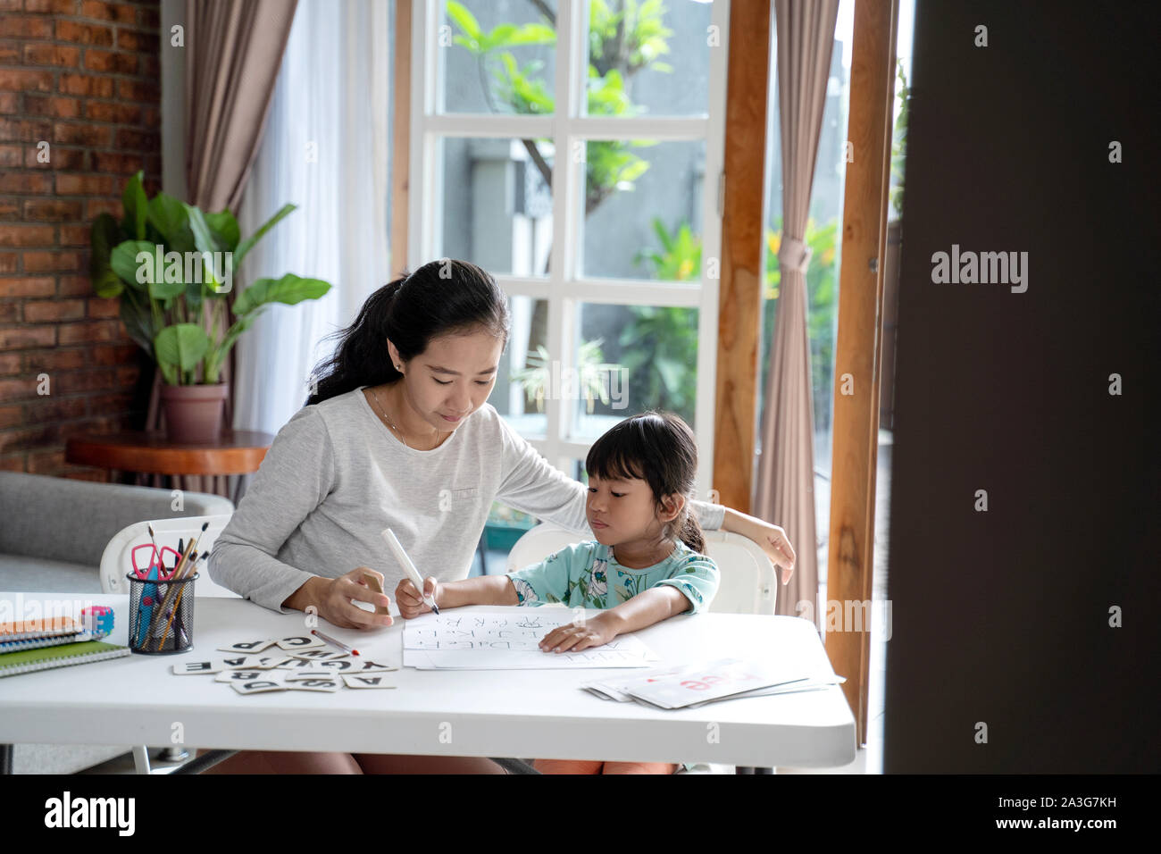 happy mother teaching her daughter the basic to read and write at home ...