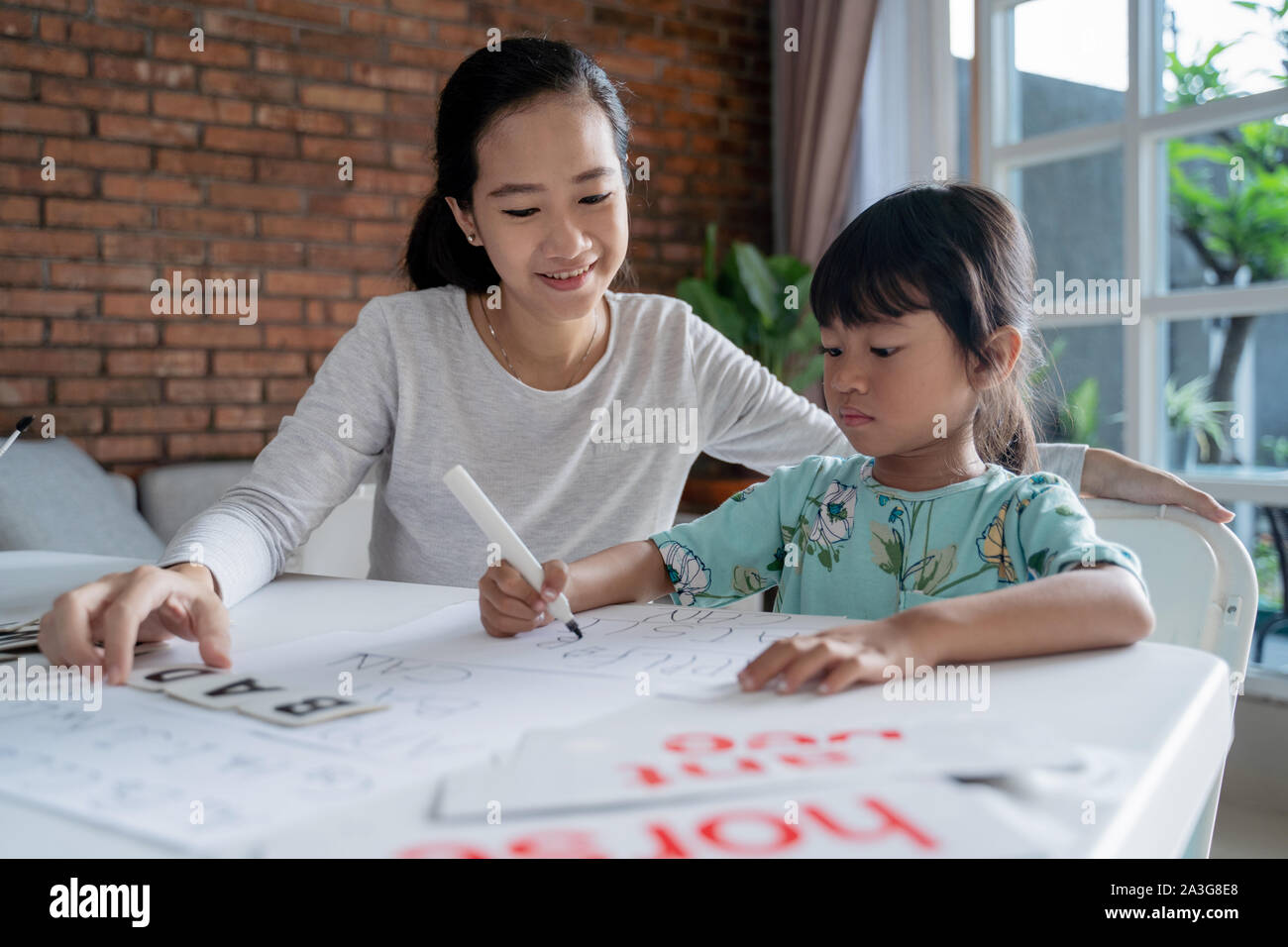 mother and daughter learning to read and write letter at home together ...