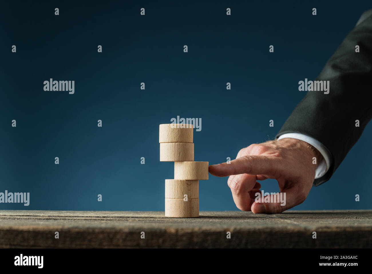Hand of a businessman pushing middle round peg into a stack of them in ...