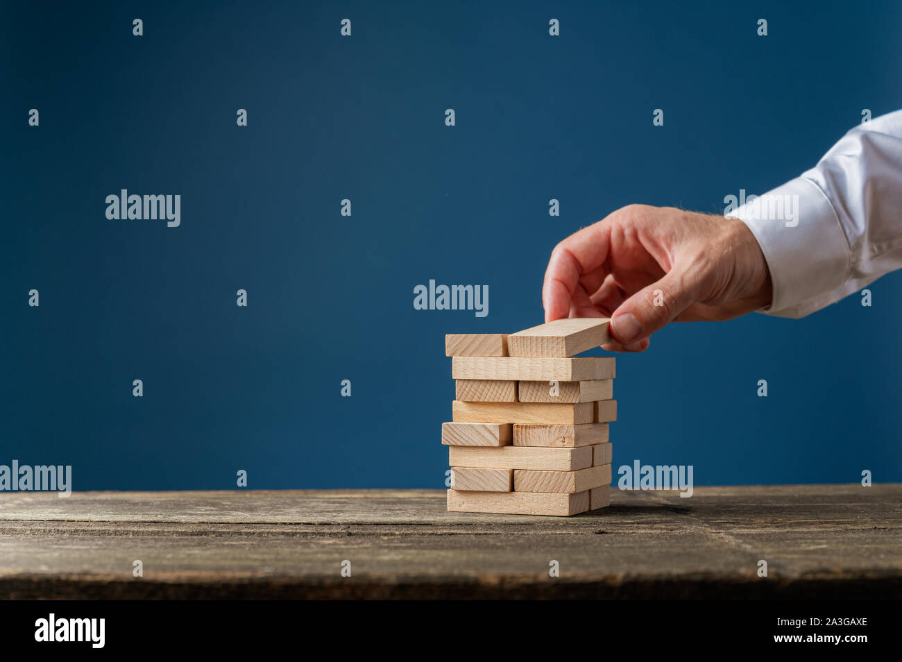 Hand of a businessman making a stack of wooden pegs in a conceptual ...