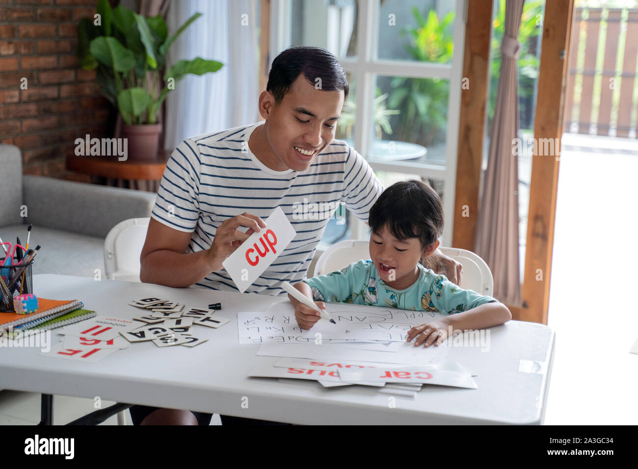 Happy Asian Father Teaching Letter To Her Daughter At Home Read And