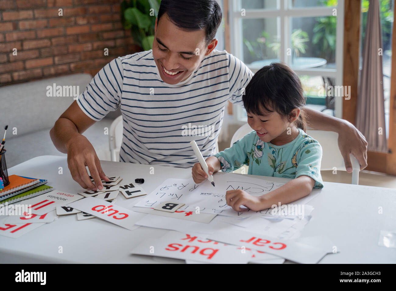 Happy Asian Father Teaching Letter To Her Daughter At Home Read And