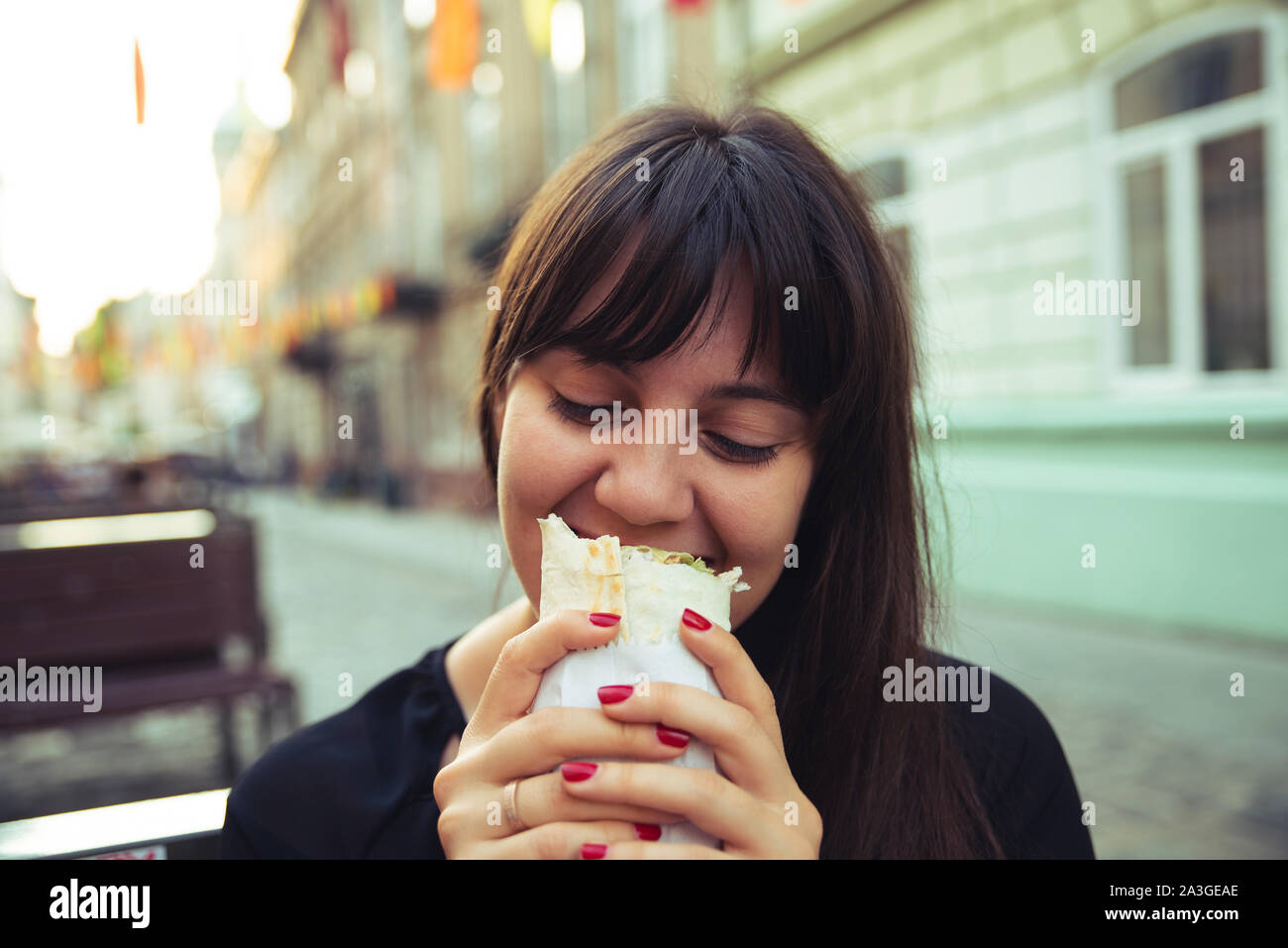 young smiling woman eating fast food outdoors Stock Photo - Alamy