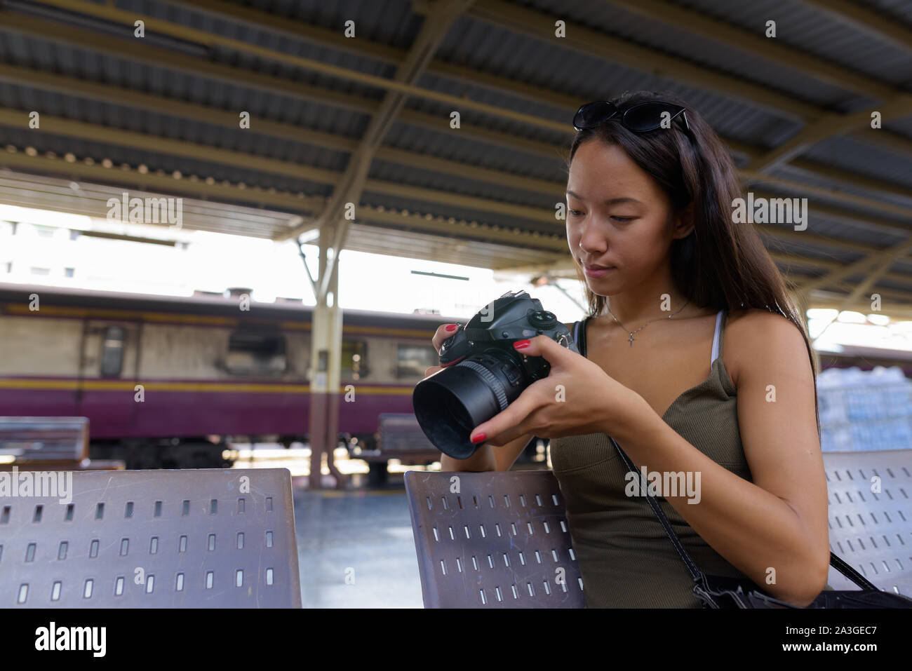 Young tourist woman sitting and using DSLR camera Stock Photo - Alamy