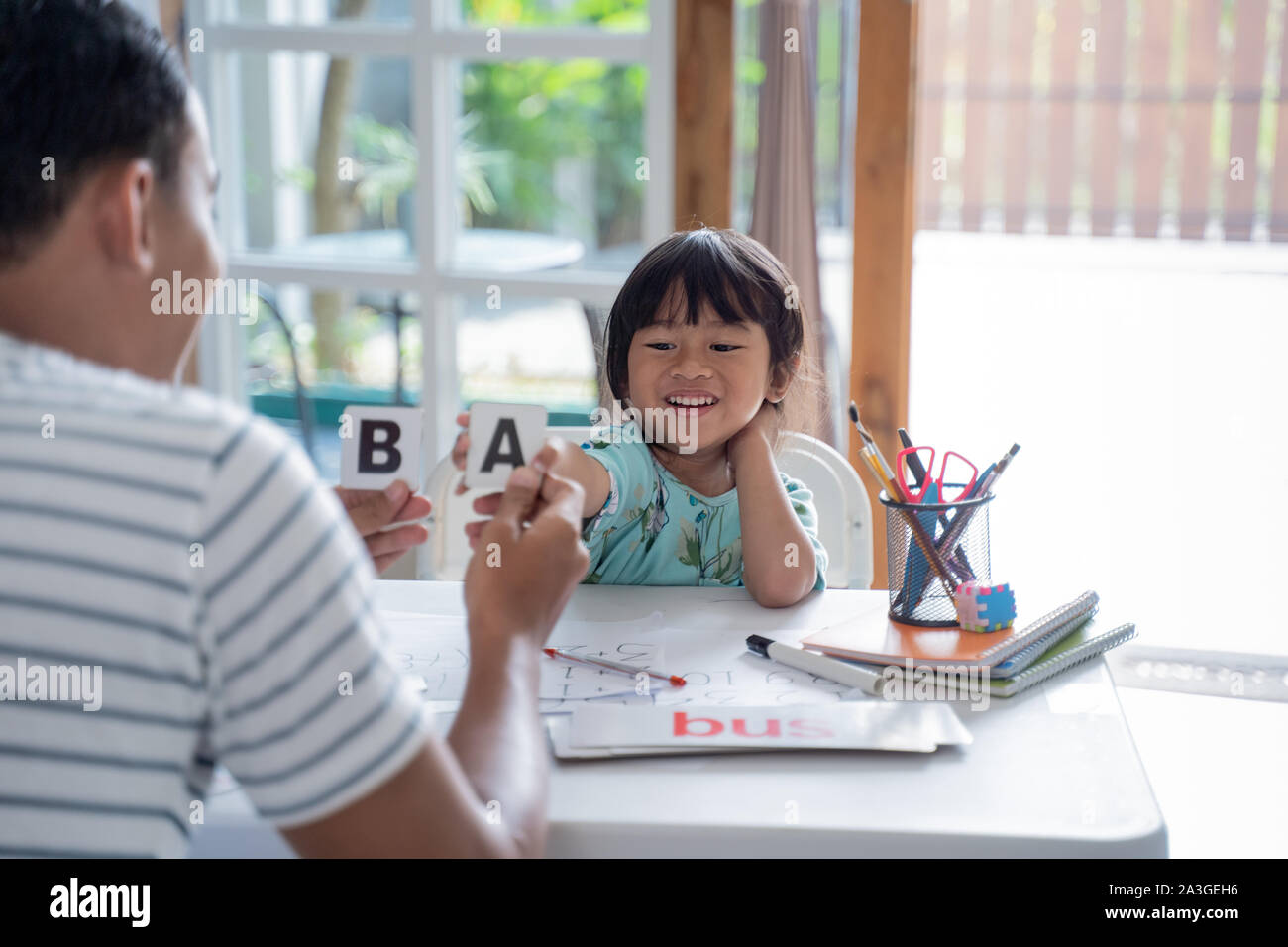 portrait of father teaching toddler how to read by using simple word ...