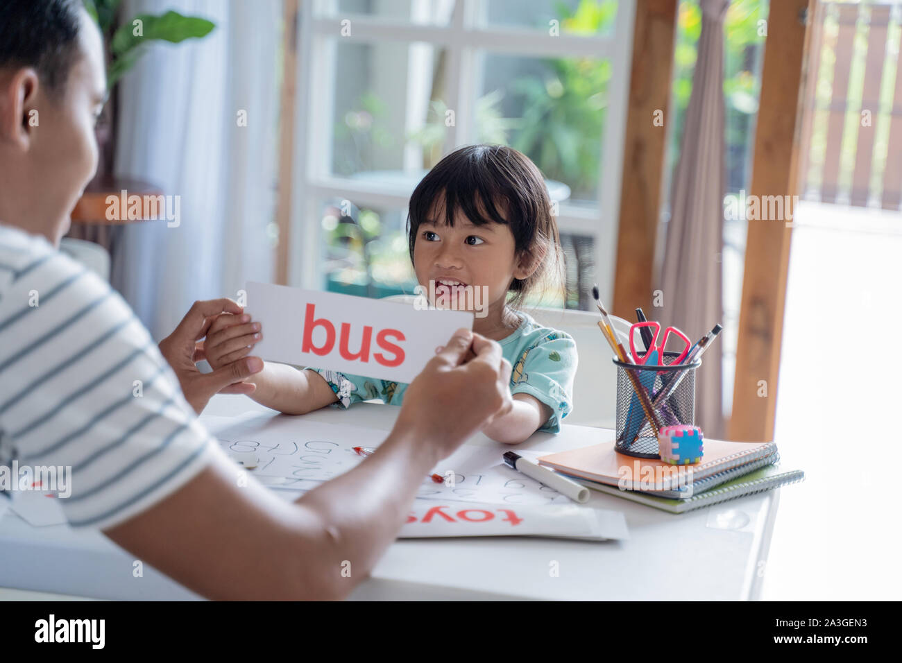 dad showing flash card with simple word to help her daughter to read ...