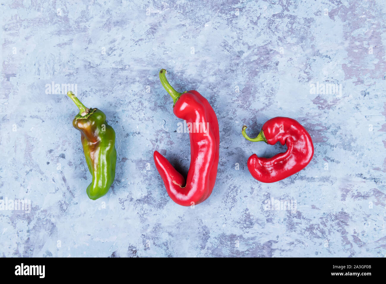 Three ugly red chili peppers on a blue grunge background, minimal style ...
