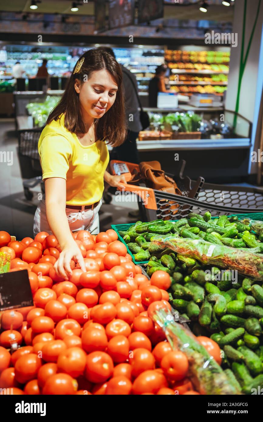 woman choosing red tomatoes from store shelf grocery shopping Stock ...
