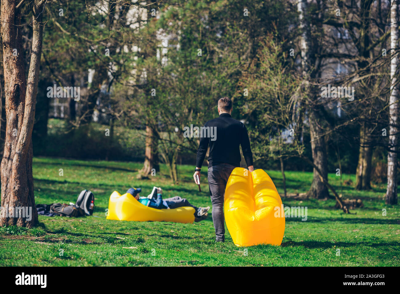 man walking with yellow inflatable mattress to place for reading book ...