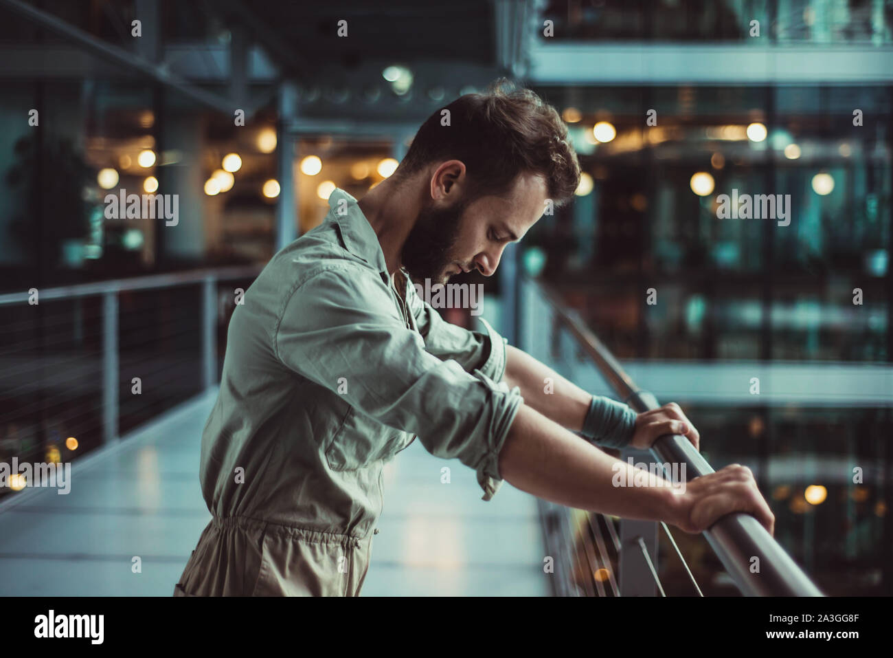 Man in mid-thirties is holding onto a railing, looking down deep in ...