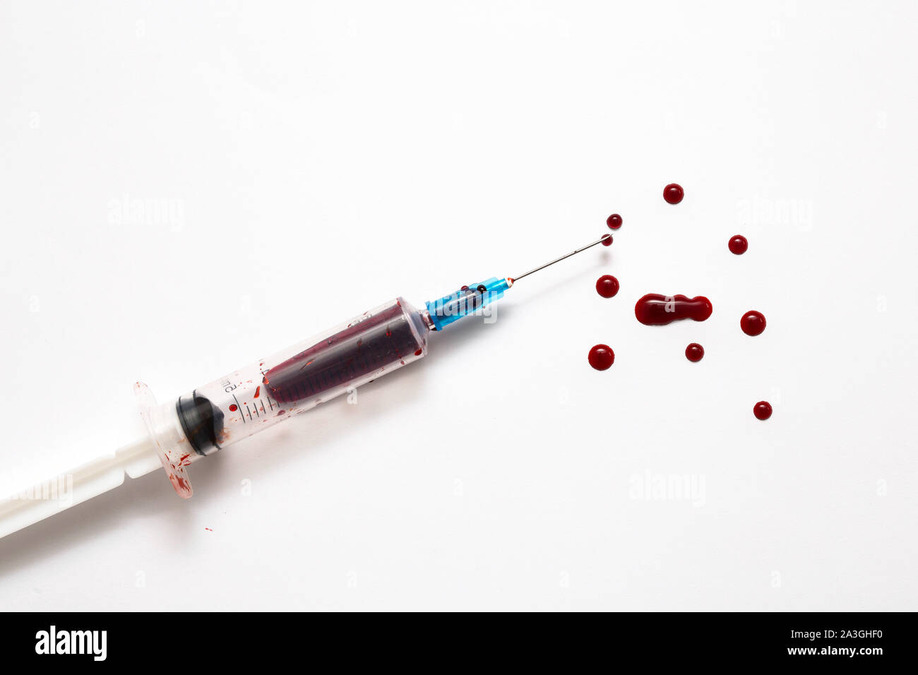 Closeup of a disposable syringe and many blood drops isolated on white ...