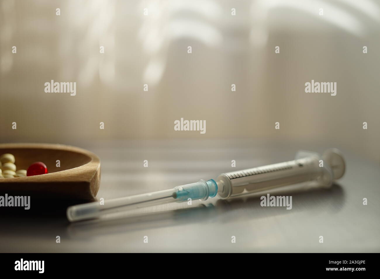 new syringe on chrome the table, with wooden spoon and pills, side view ...