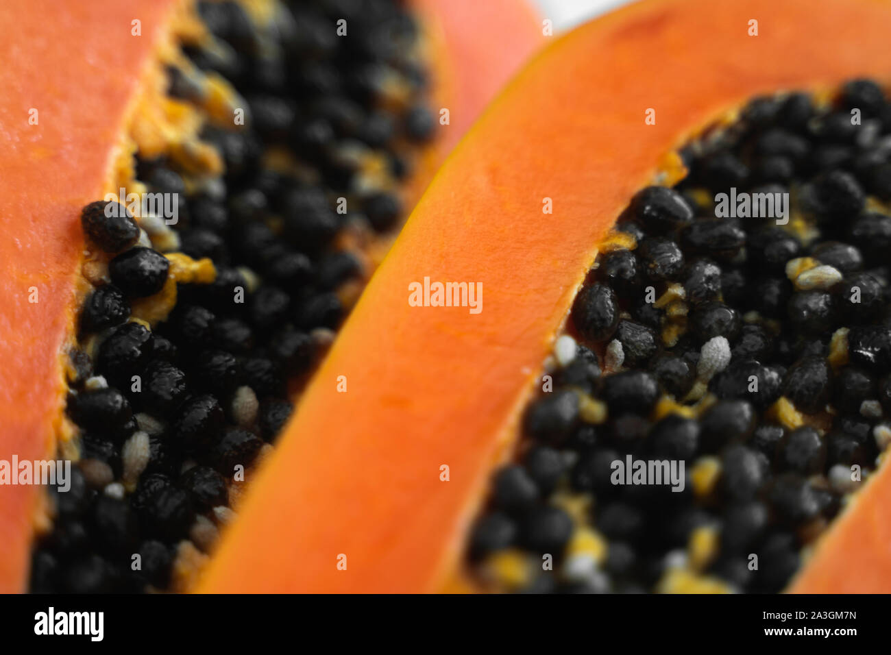 Half cut ripe papaya with seed on a white plate. Slices of sweet papaya ...