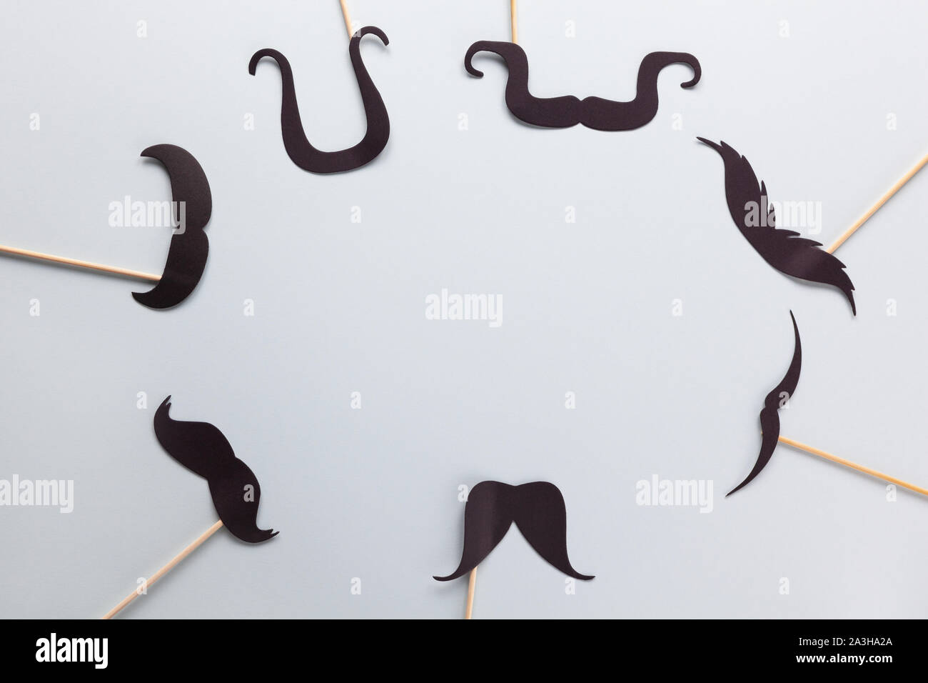Accessories in form of black moustache on sticks on grey background ...