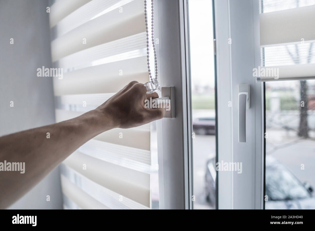 Man holding window handle on a plastic window with white fabric roller ...