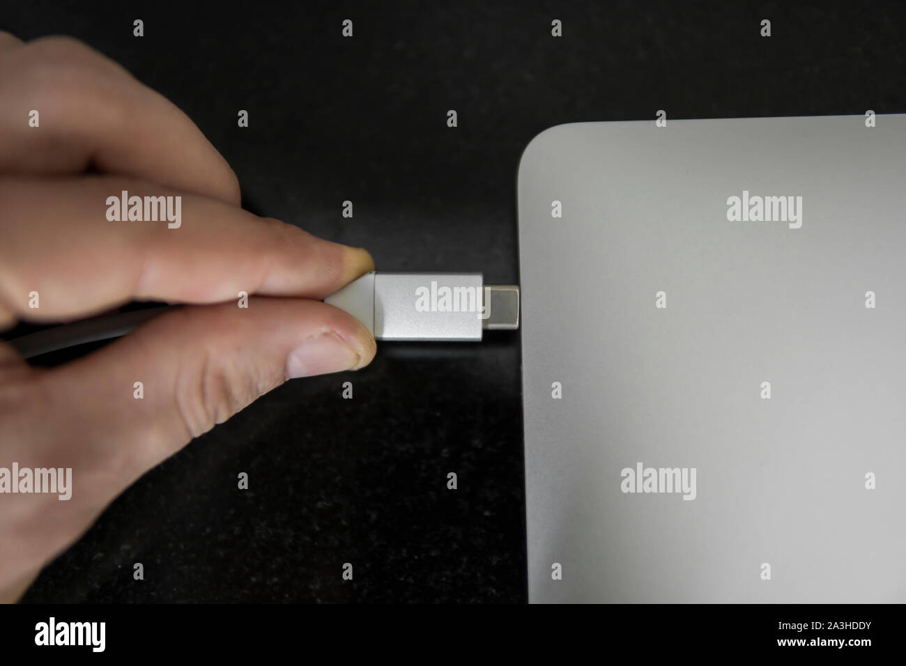 Male hand plugging white USB-C Type C cable into a port on a grey ...