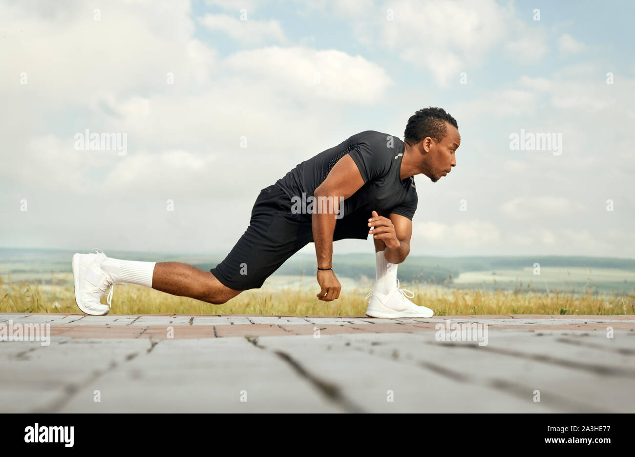 Track and field athlete doing exercises with stretching for feet in ...