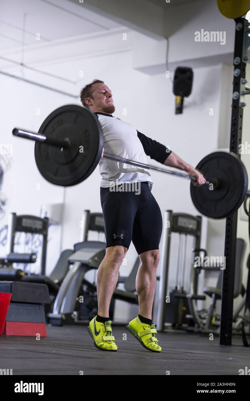 A young white male athlete performs various lifts and bodyweight ...