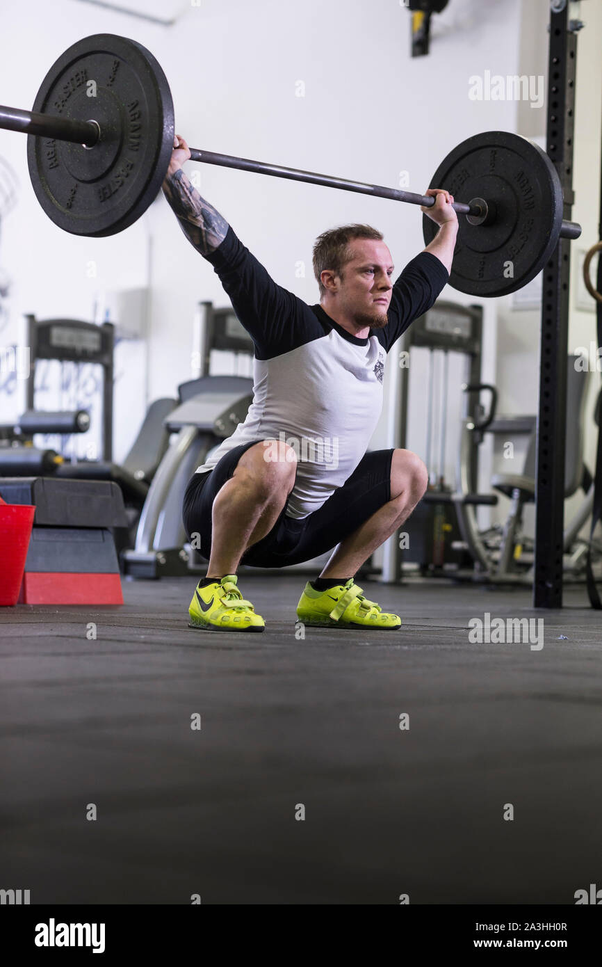 A young white male athlete performs various lifts and bodyweight ...