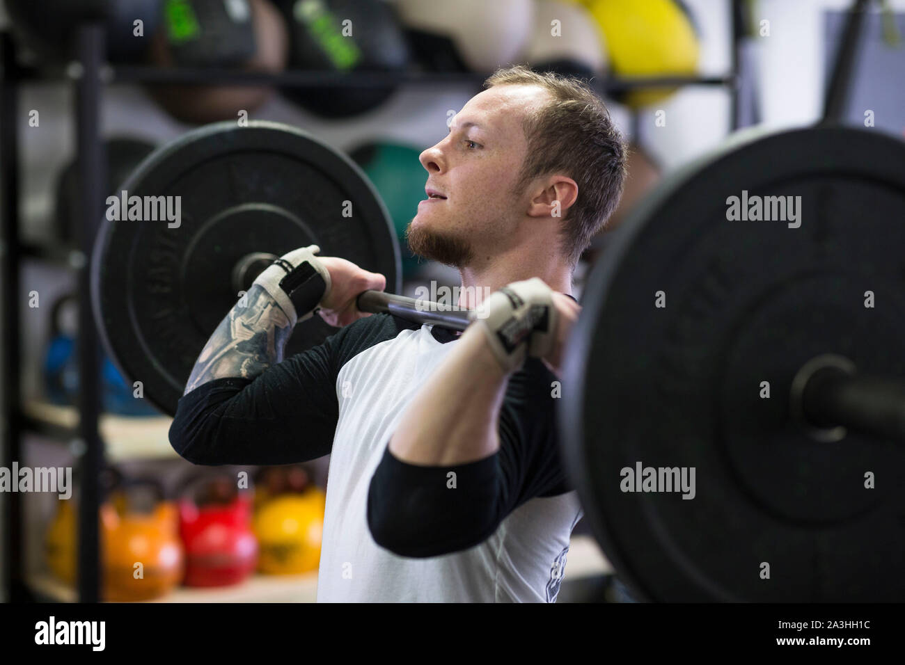 A young white male athlete performs various lifts and bodyweight ...