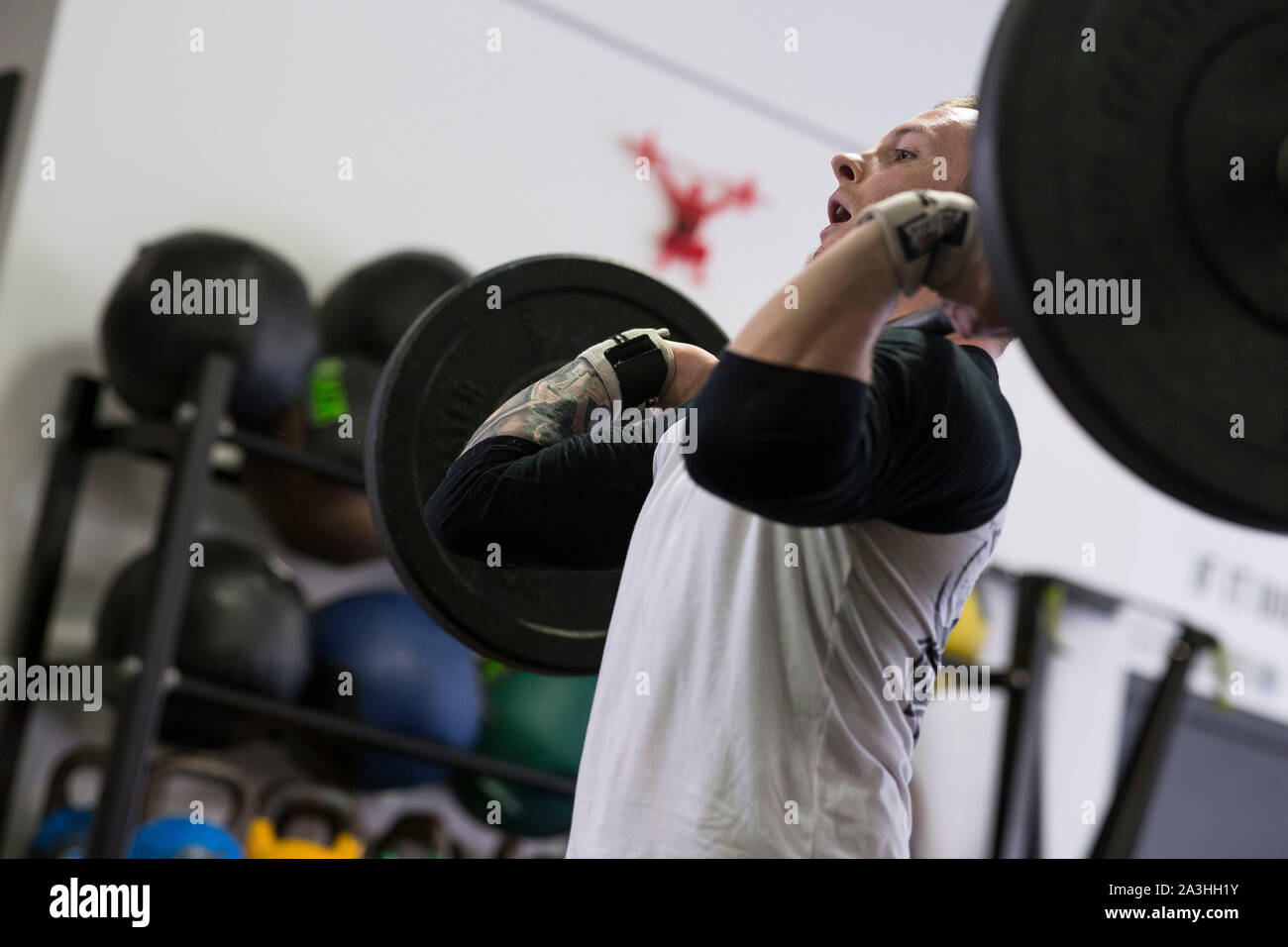 A young white male athlete performs various lifts and bodyweight ...