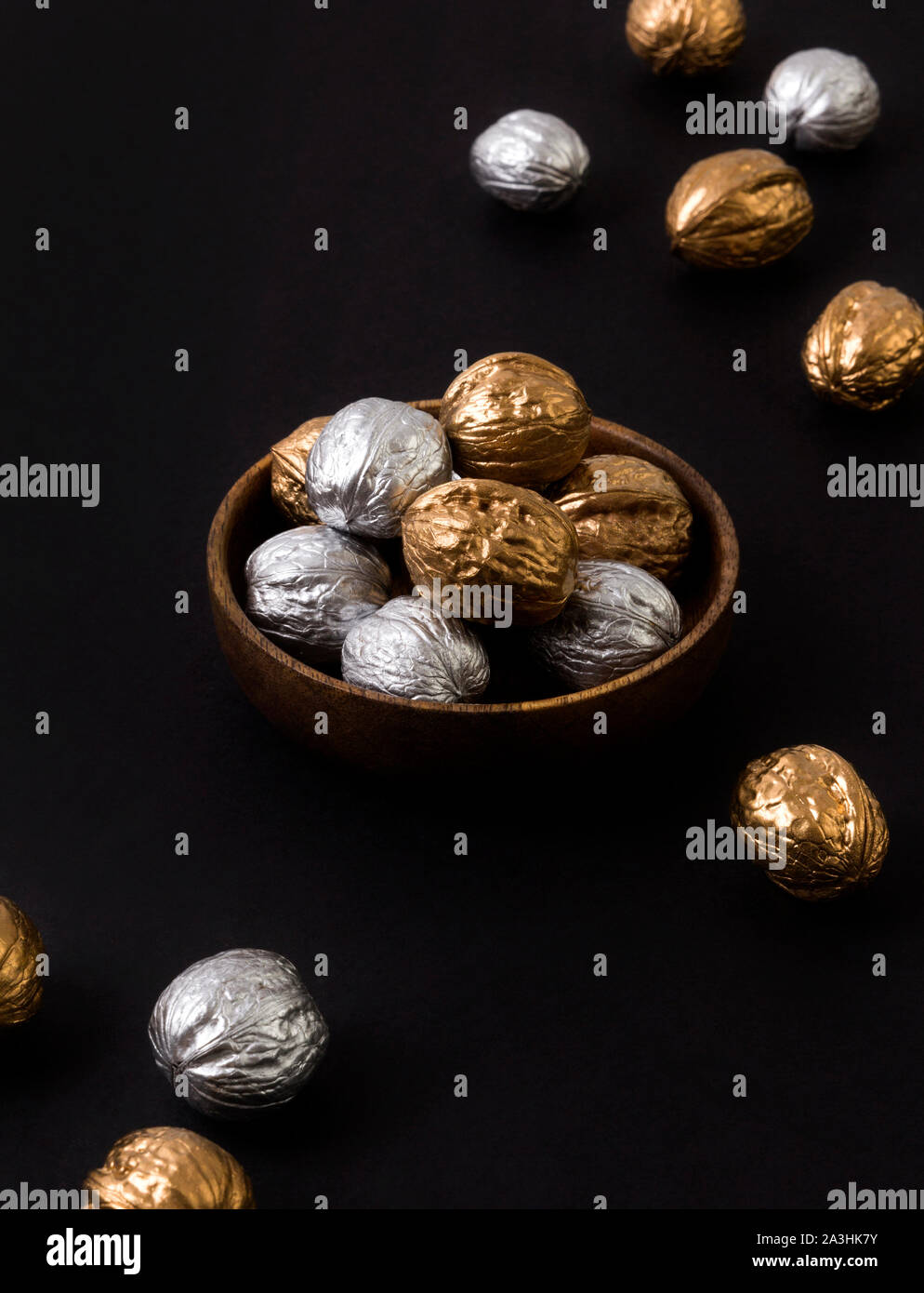 Painted golden and silver walnuts on wooden plate on black background ...