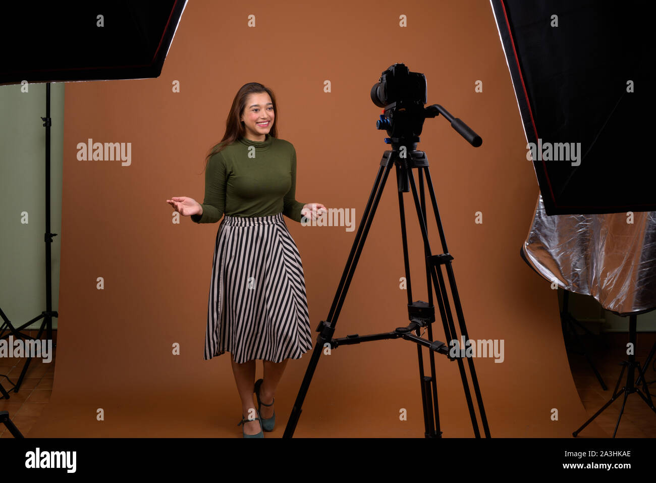 Young beautiful Indian woman vlogging against brown background Stock ...