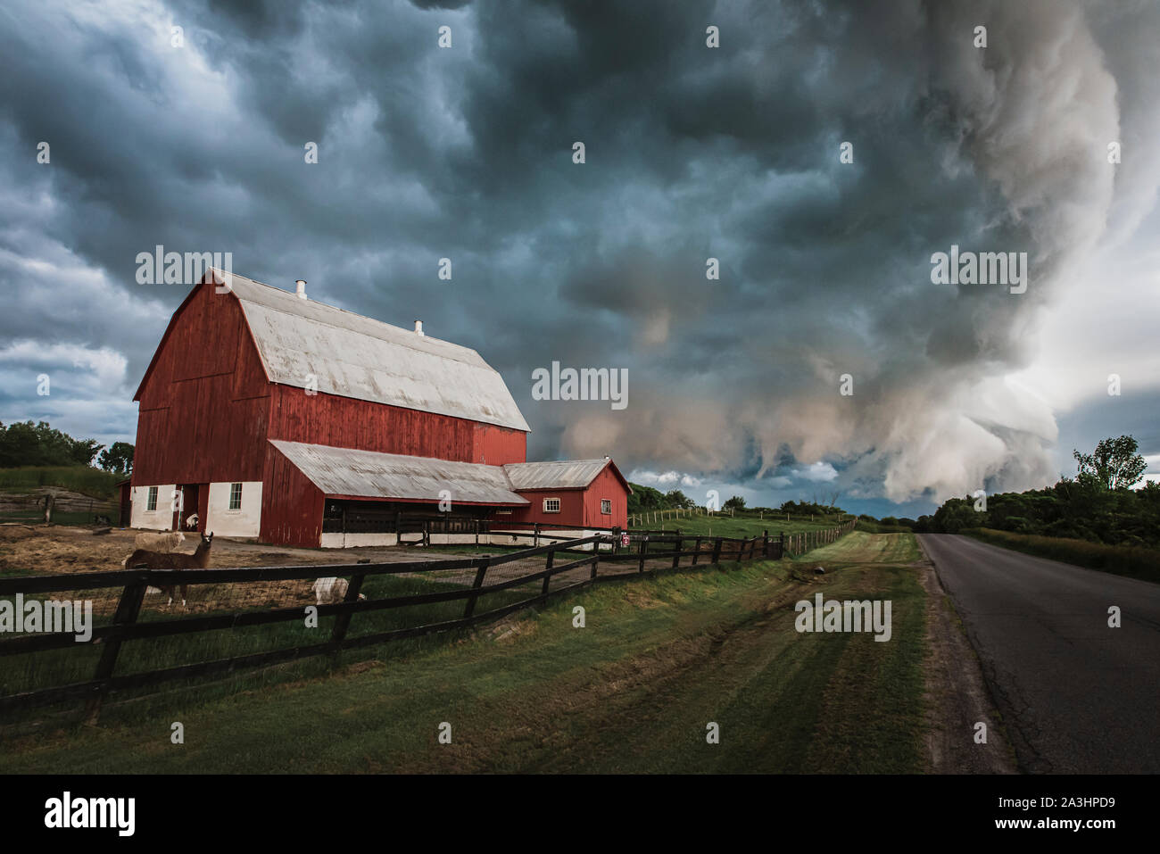 Dramatic storm clouds moving over a red barn on a country road Stock ...