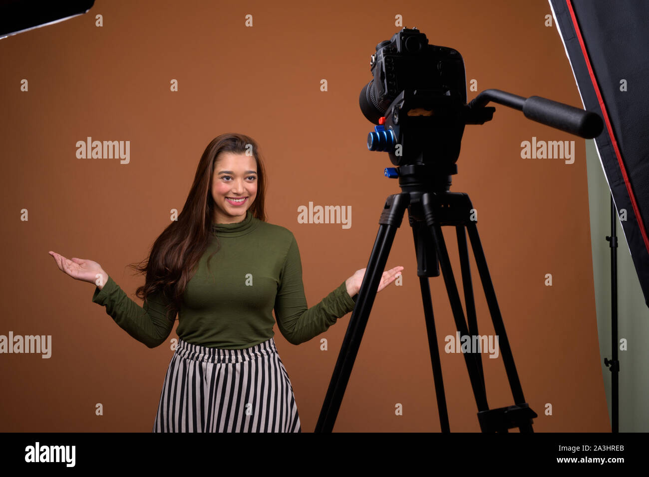 Young beautiful Indian woman vlogging against brown background Stock ...