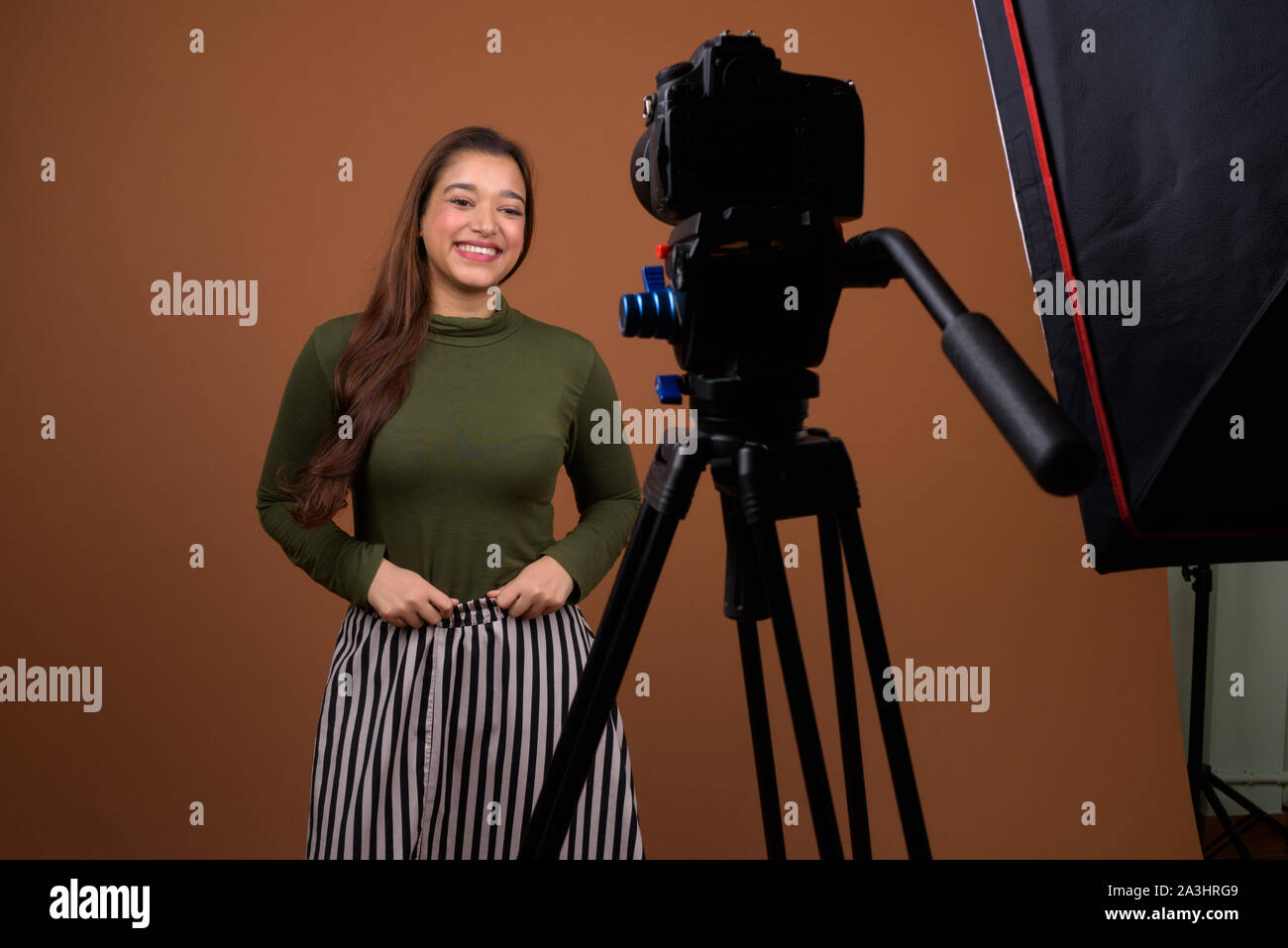 Young beautiful Indian woman vlogging against brown background Stock ...