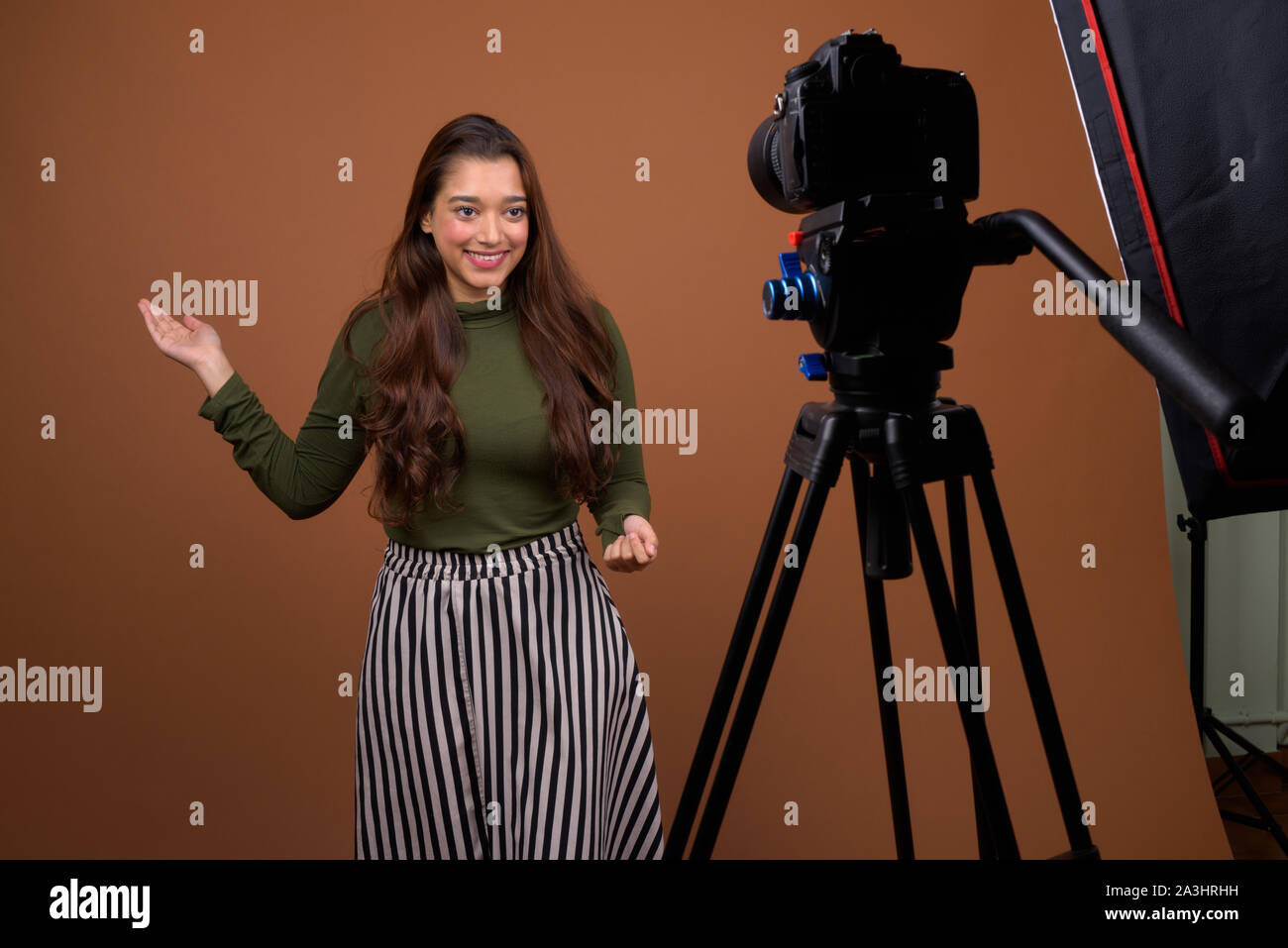 Young beautiful Indian woman vlogging against brown background Stock ...
