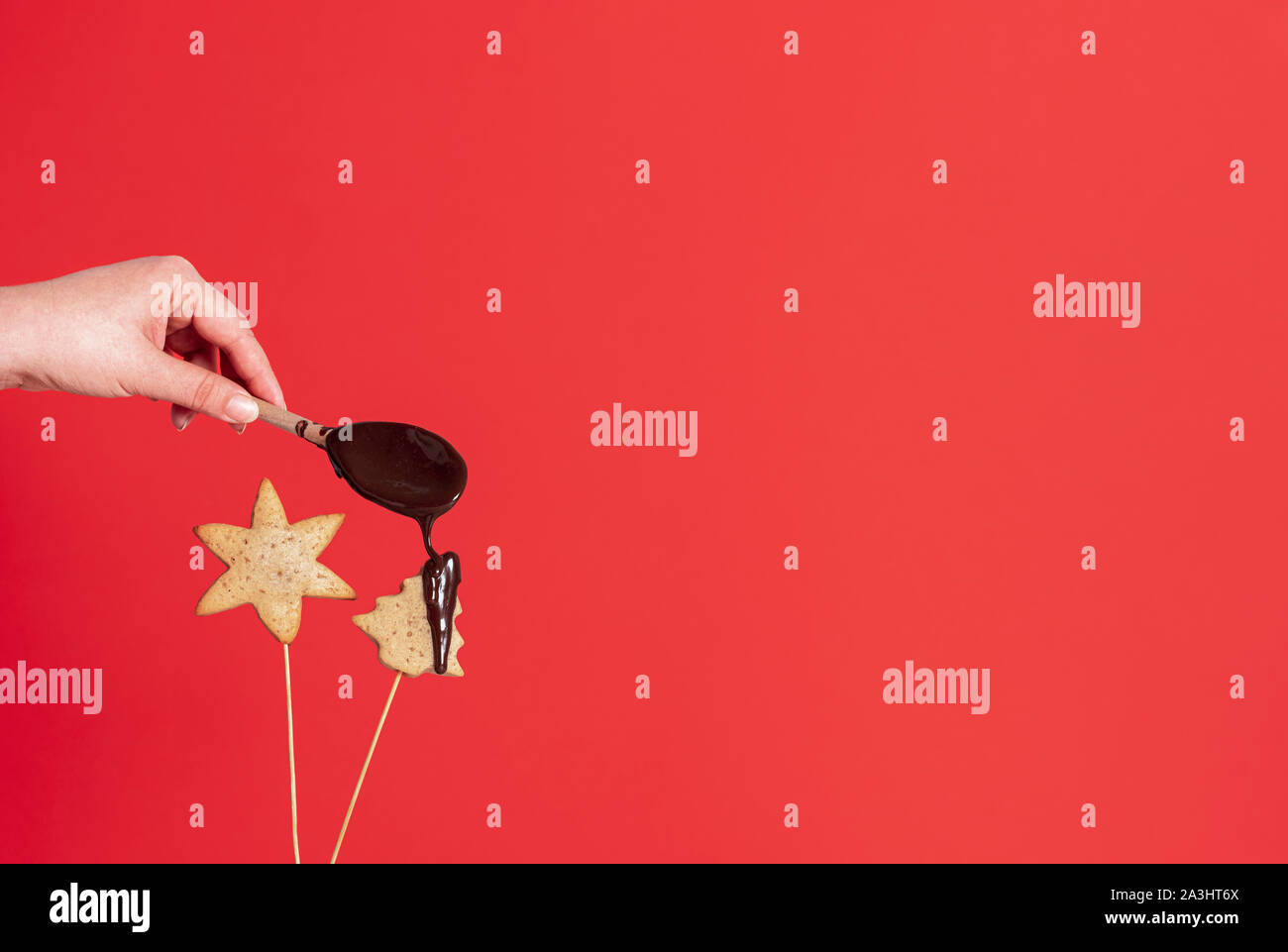 Woman glazing gingerbread cookies with melted dark chocolate from a ...