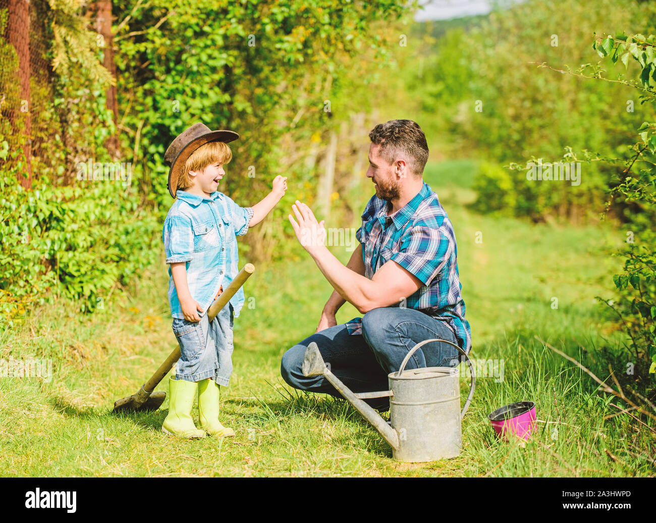 small boy child help father in farming. use watering can and pot ...
