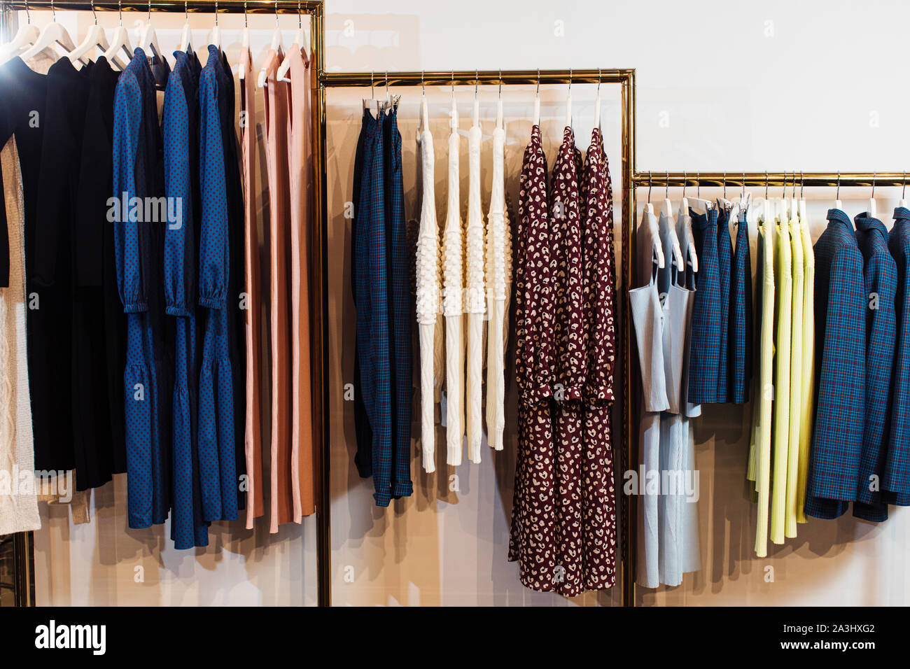 Close-up view of various stylish clothes hanging on hangers in boutique ...