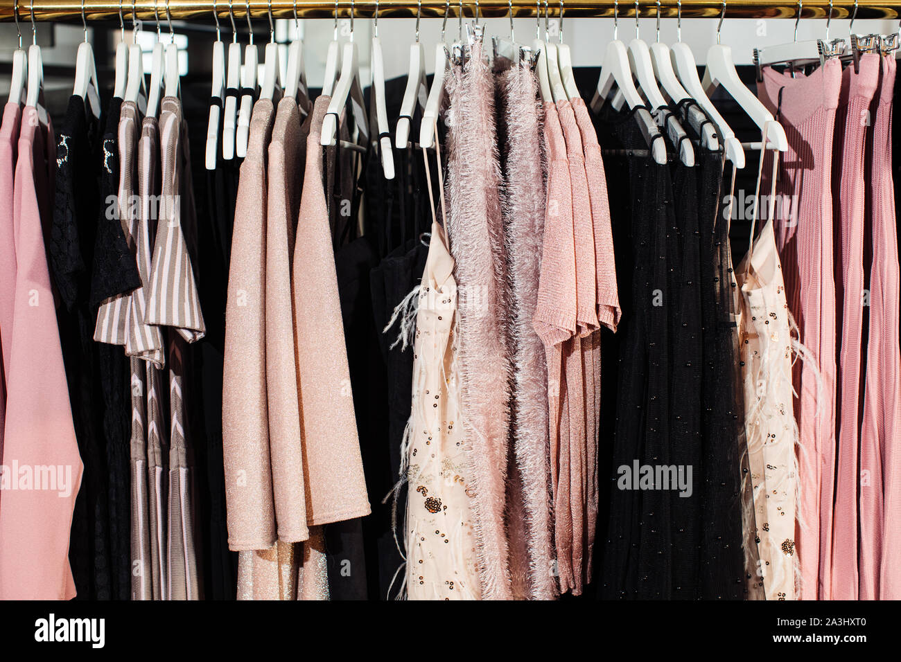 Close-up view of various stylish clothes hanging on hangers in boutique ...