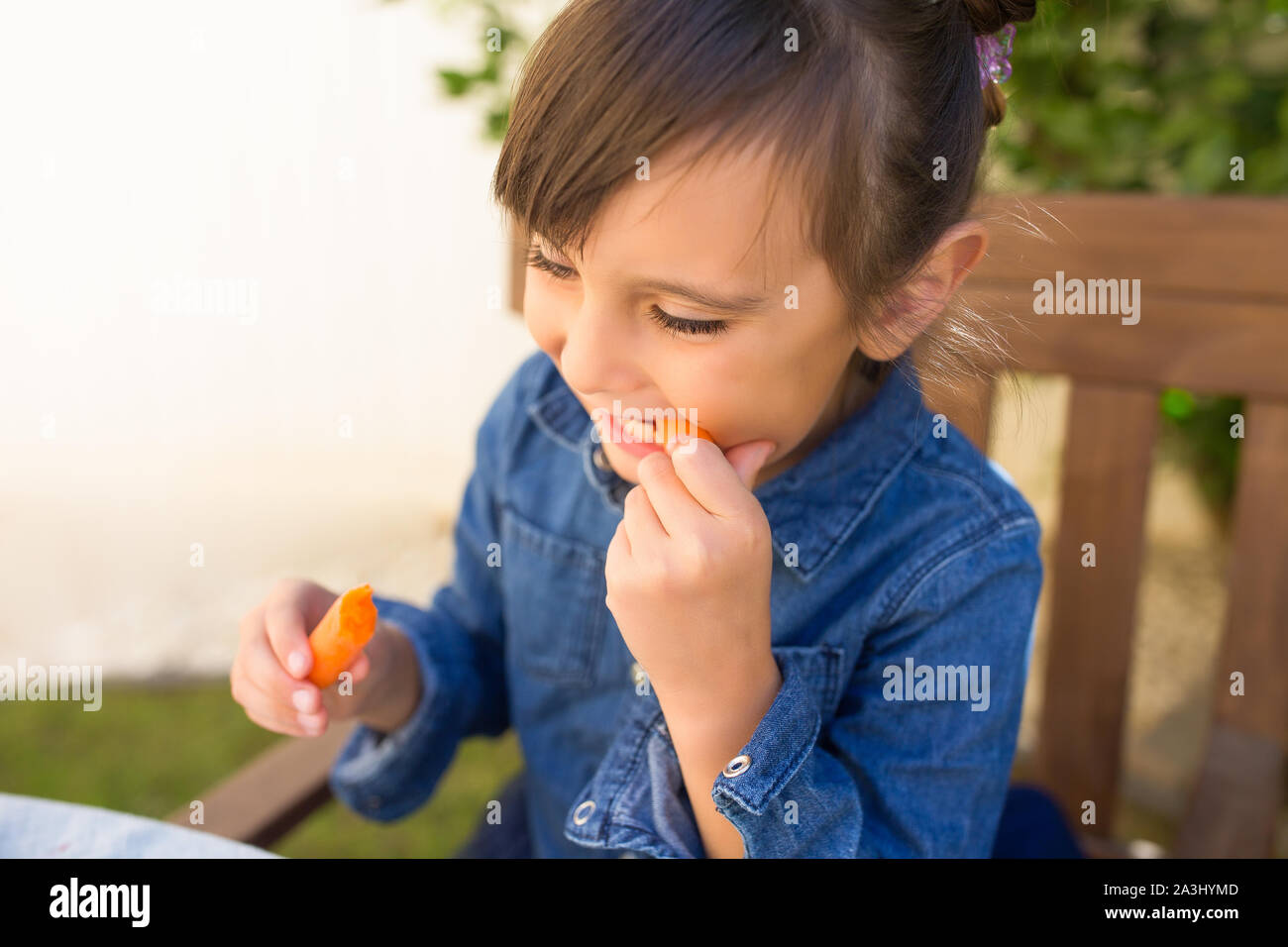 Girl biting baby carrot sticks Stock Photo - Alamy