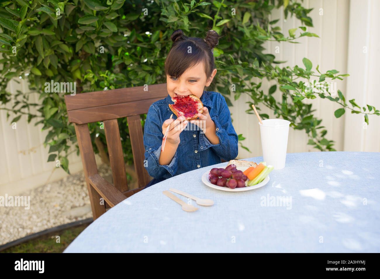 Girl biting a bread with jam on it Stock Photo - Alamy