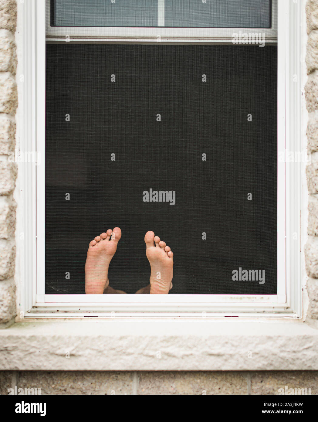 Open window with a child's feet on the ledge against the screen Stock ...