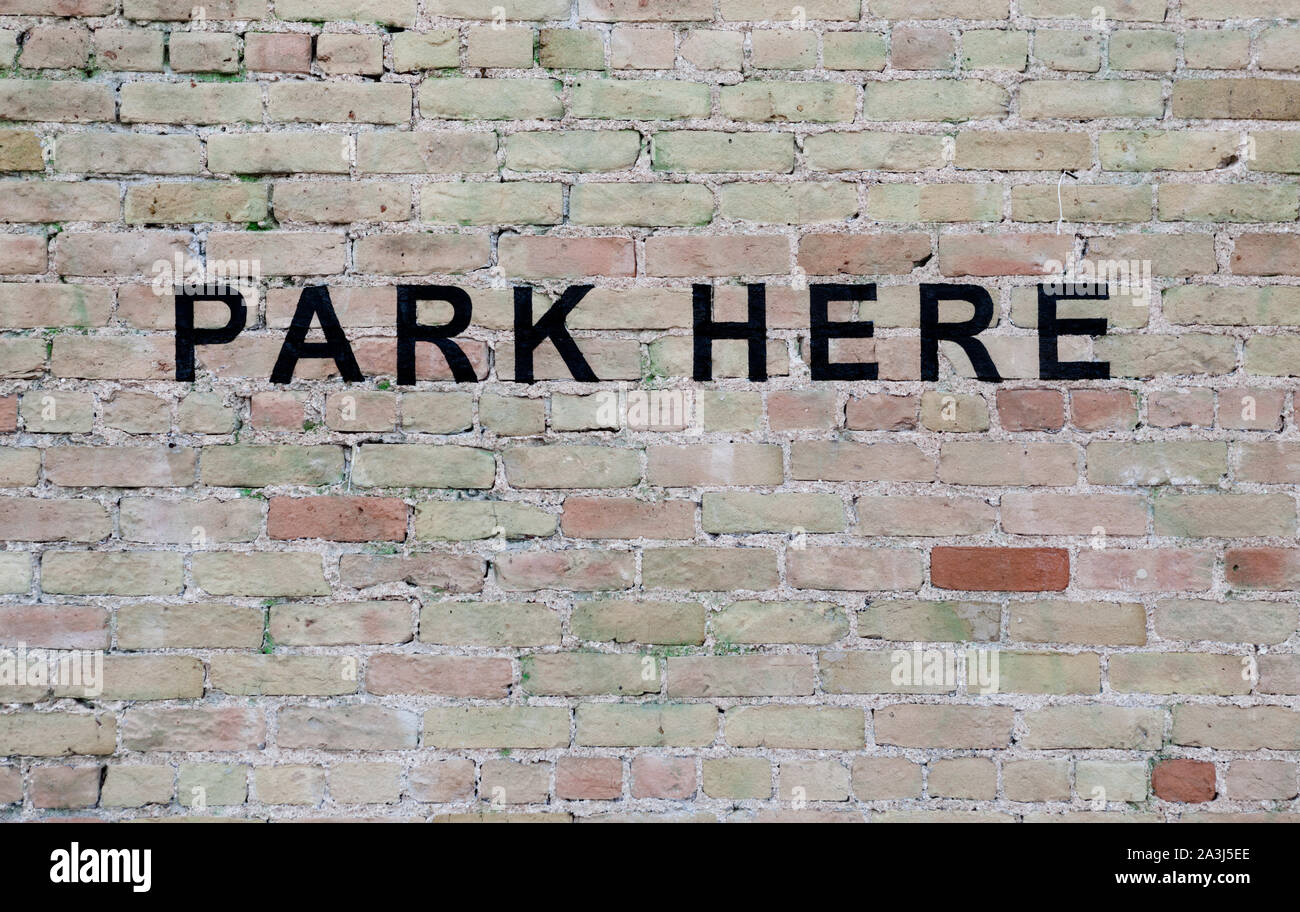 Park Here sign written on brick wall background Stock Photo - Alamy