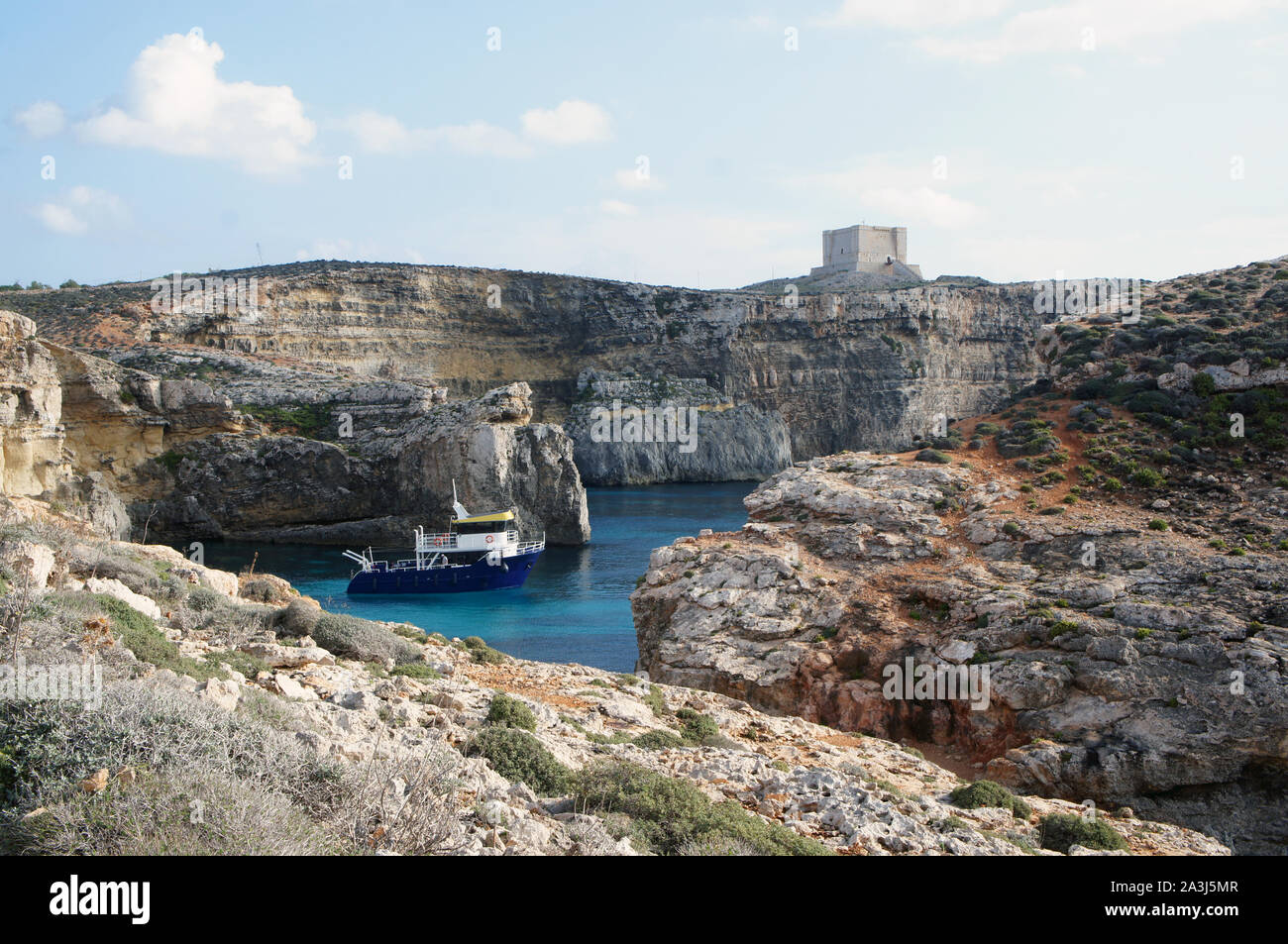 Single boat on the blue lagoon surrounded by rocky cliffs with a tower ...