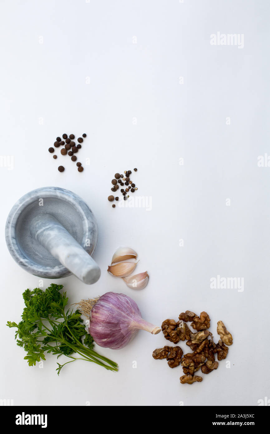 Mortar and pestle, garlic, spices and nuts on a white background ...