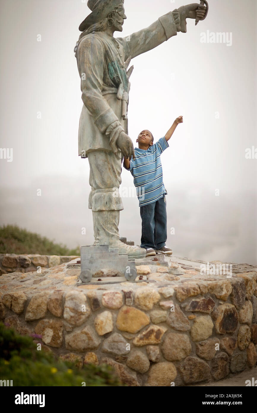 Young boy gesturing while standing next to a large statue Stock Photo ...