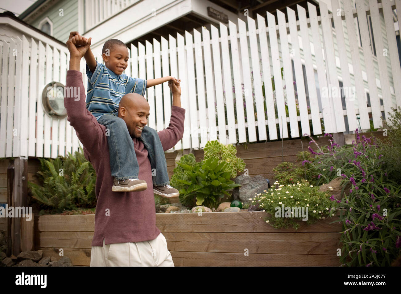 Father carrying his young son on his shoulders down a suburban street ...