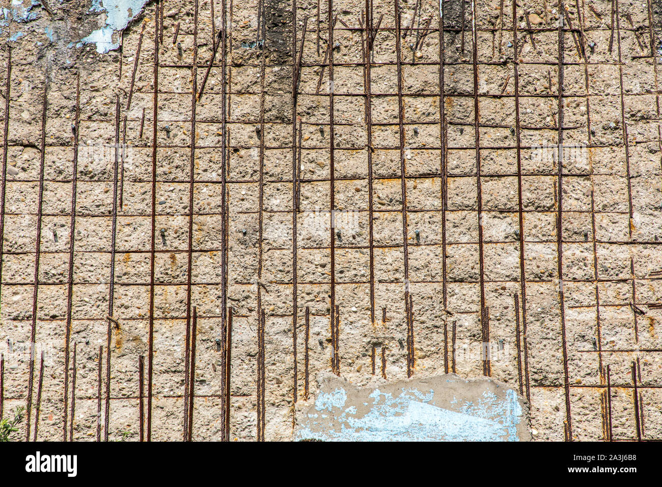 Concrete wall, chipped concrete, the reinforcing irons become visible ...