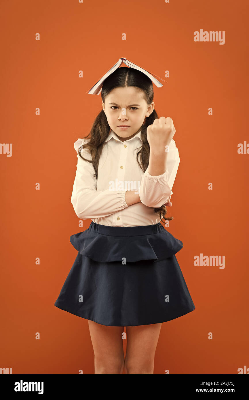 She hates reading. Angry small child tired of reading book on orange ...