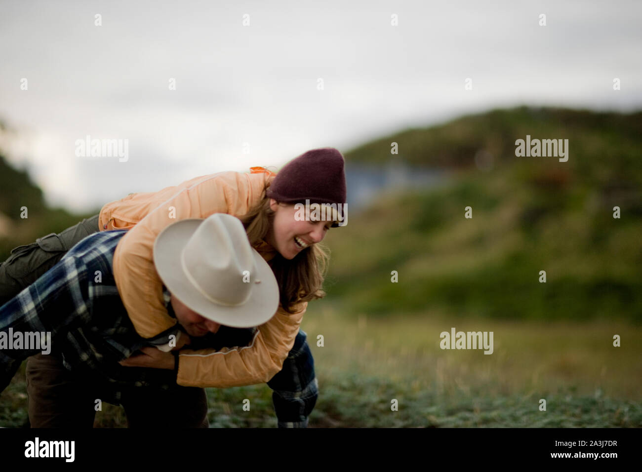 Man giving woman a piggy back ride in field Stock Photo - Alamy