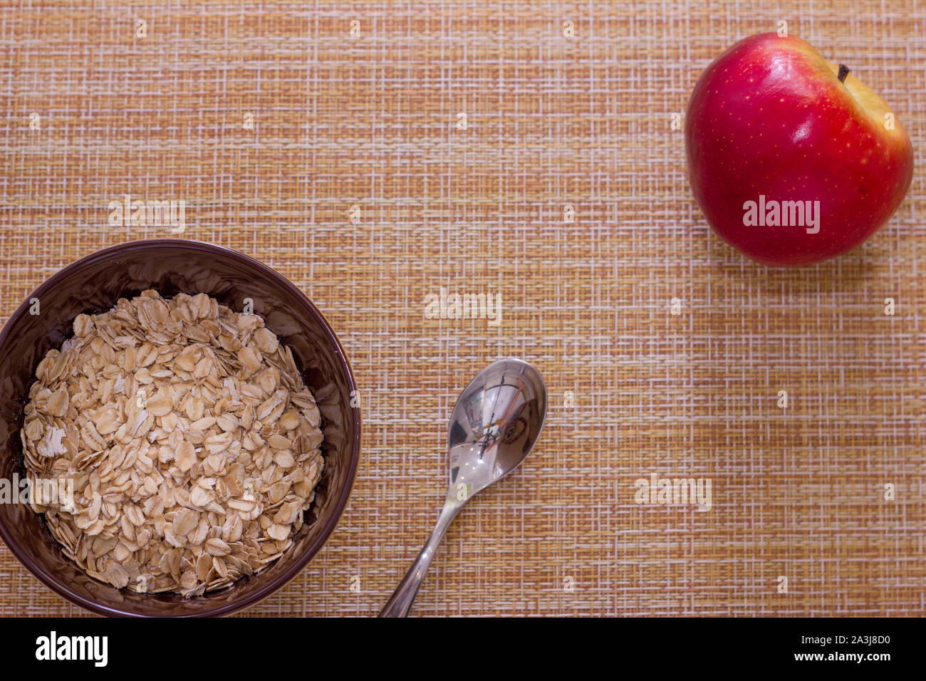 Cup with raw oatmeal and fresh red apple on gunny background for ...
