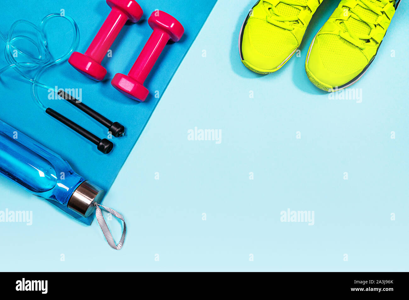 Athlete's set with pink dumbbells, bottle of water, jump rope on blue ...