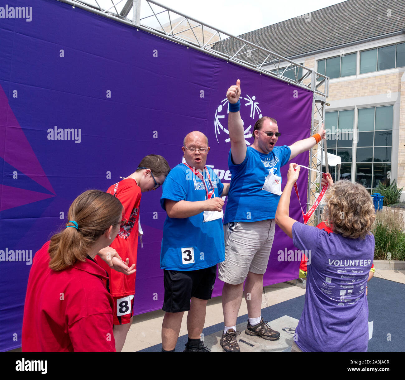 Special Olympics winner standing on top tier of podium raises hands ...