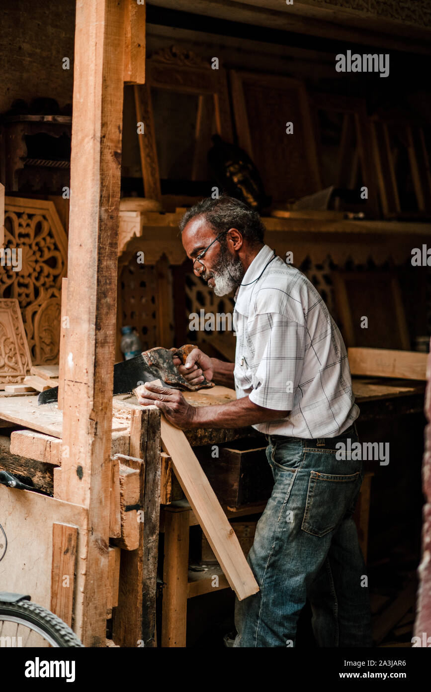 Muslim man working the wood on the door of his house with a saw Stock ...